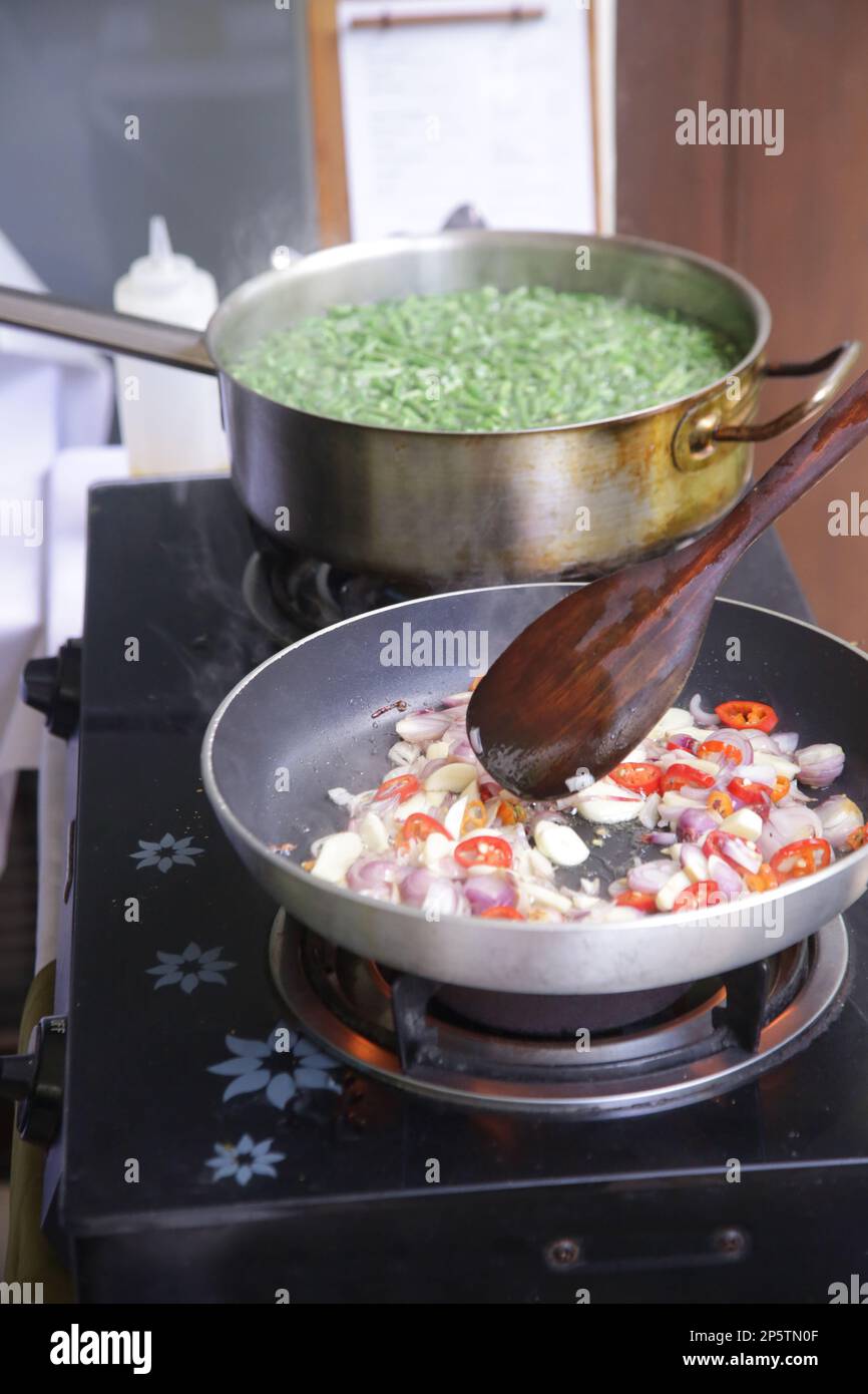 Preparation of vegetables on the stove, sauting onion and boiling green ...