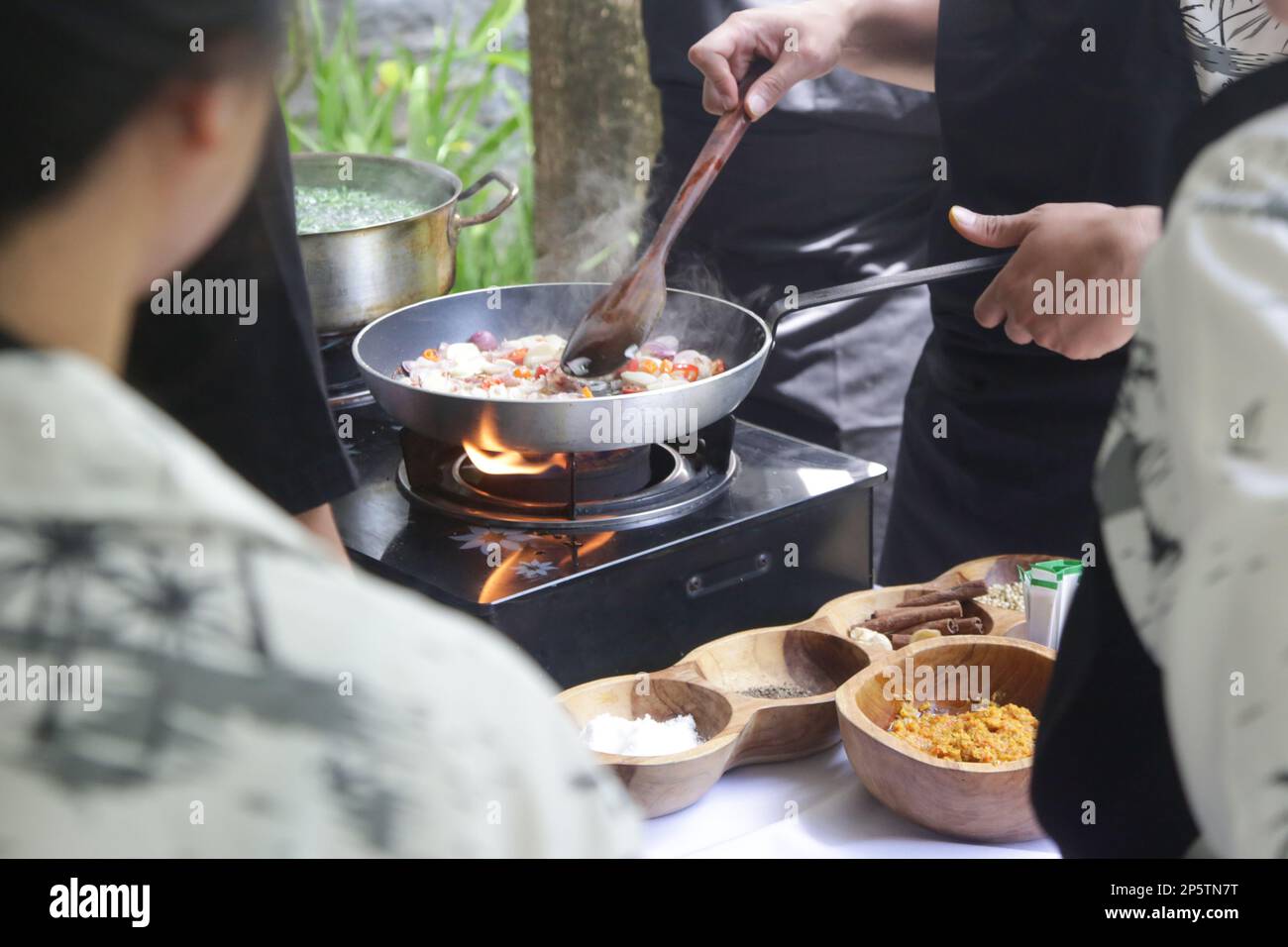 Adult students learning recipe and preparing meal in cooking class ...