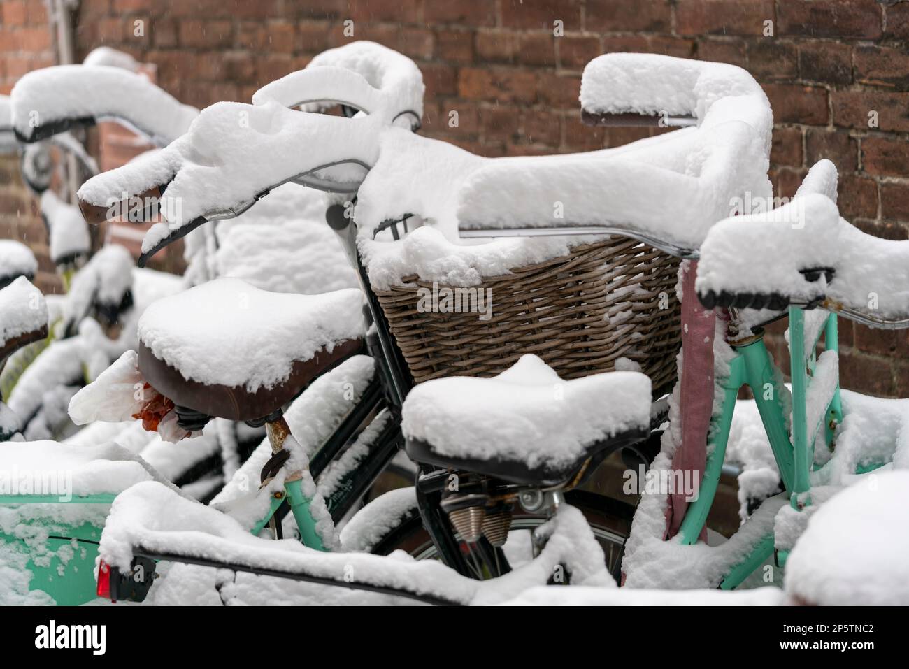 Parked bikes covered in snow with depth of field in an alleyway in ...