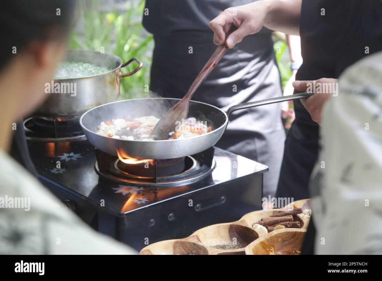 Adult students learning recipe and preparing meal in cooking class ...