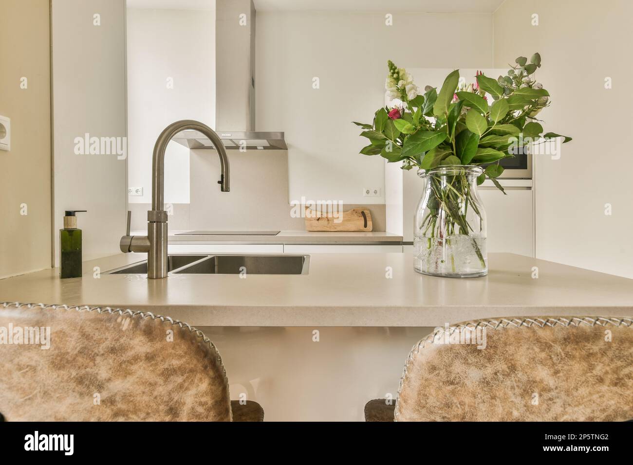 some flowers in a vase on a kitchen island with two bar stools and a ...