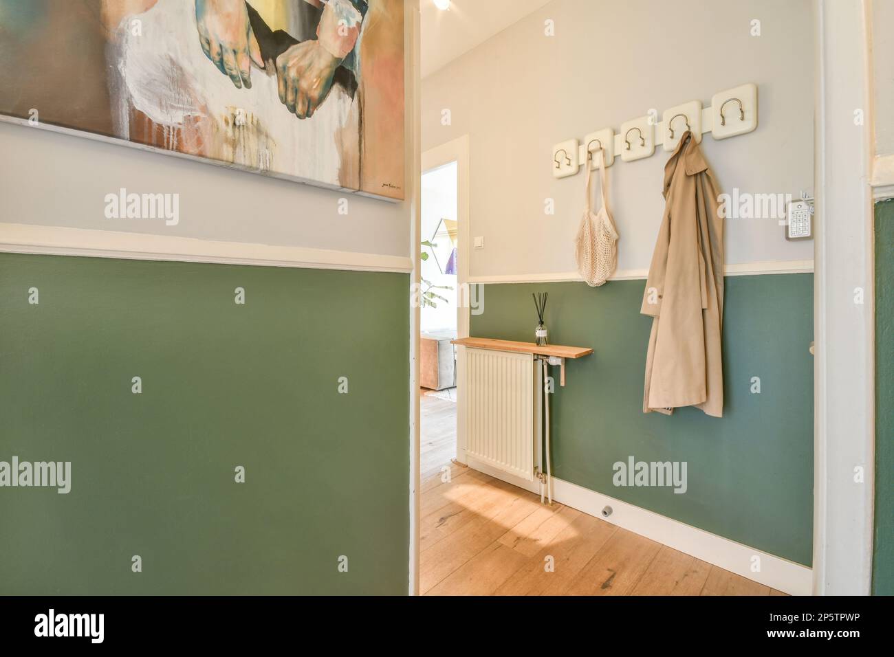 a painting hanging on the wall next to a coat rack in a room with green ...