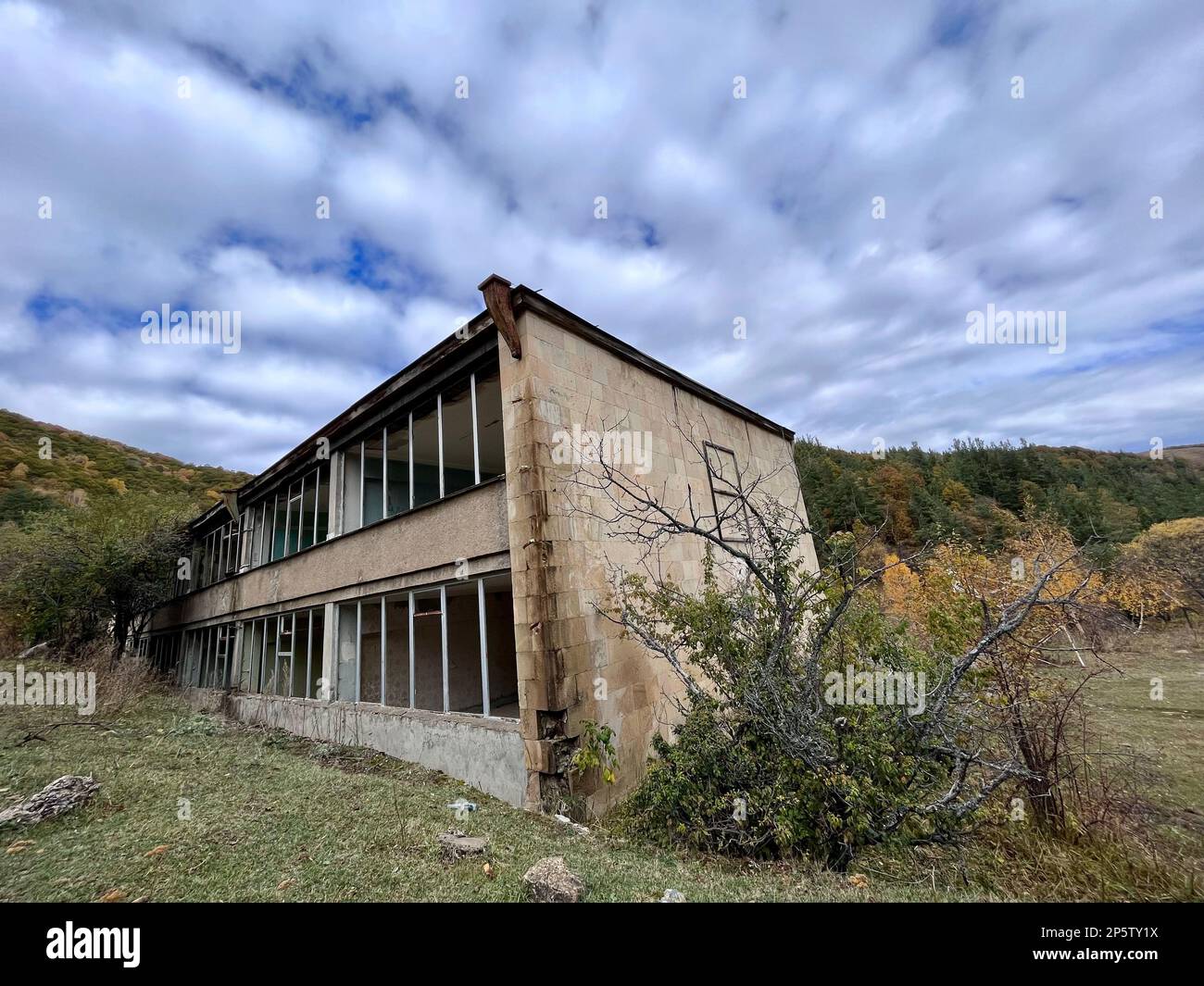 A derelict structure stands amongst overgrown vegetation, giving off a ...