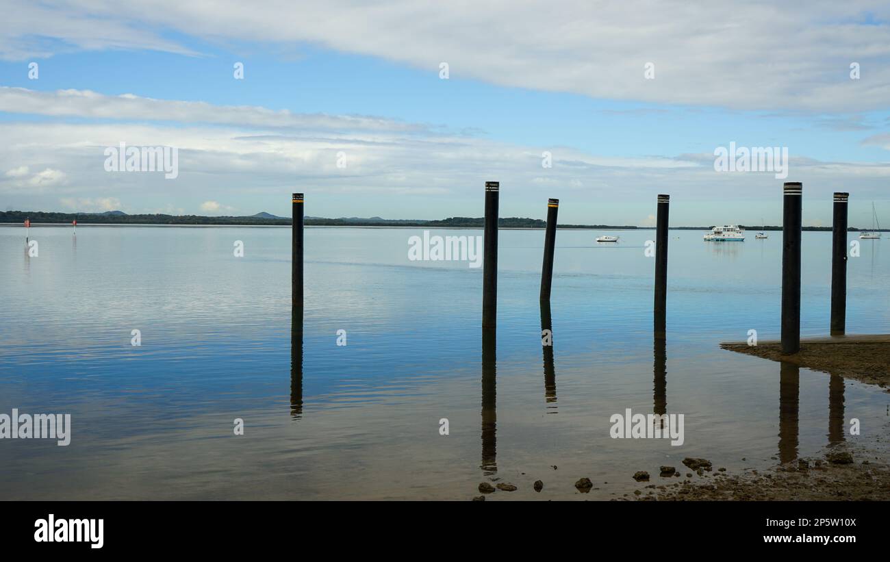 Bollards and beautiful, cloudy morning sky reflected in the calm waters ...
