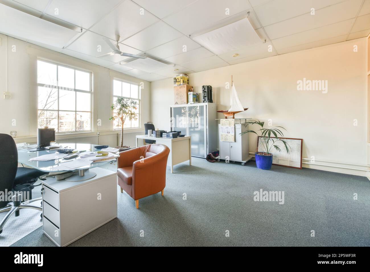 an office with two desks and one chair in front of the other ...