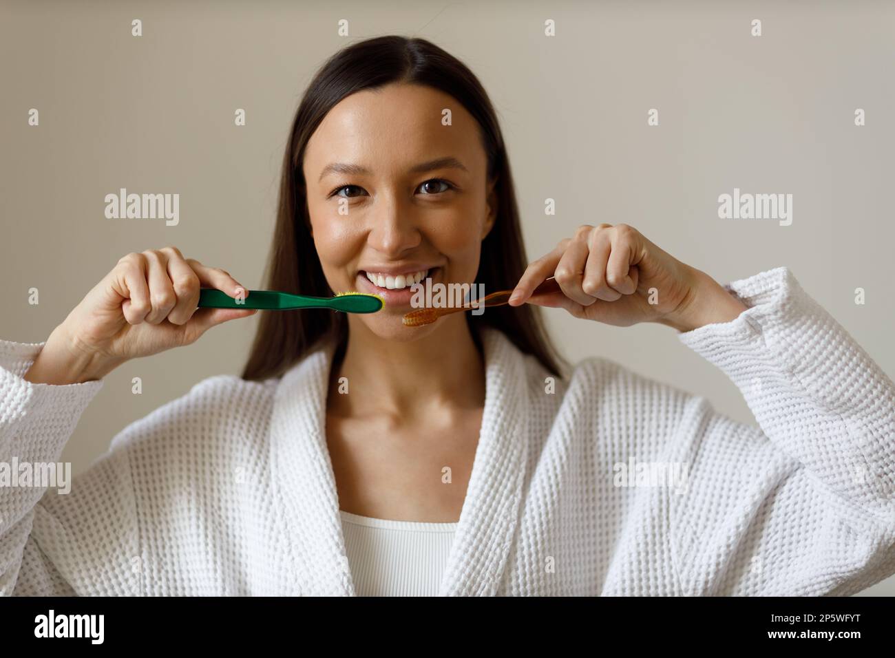 Portrait of smiling attractive cheerful young woman engaged in everyday procedures after shower ...