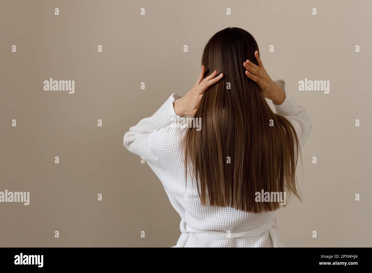 Young woman with healthy long smooth hair in white bathrobe, rear view ...