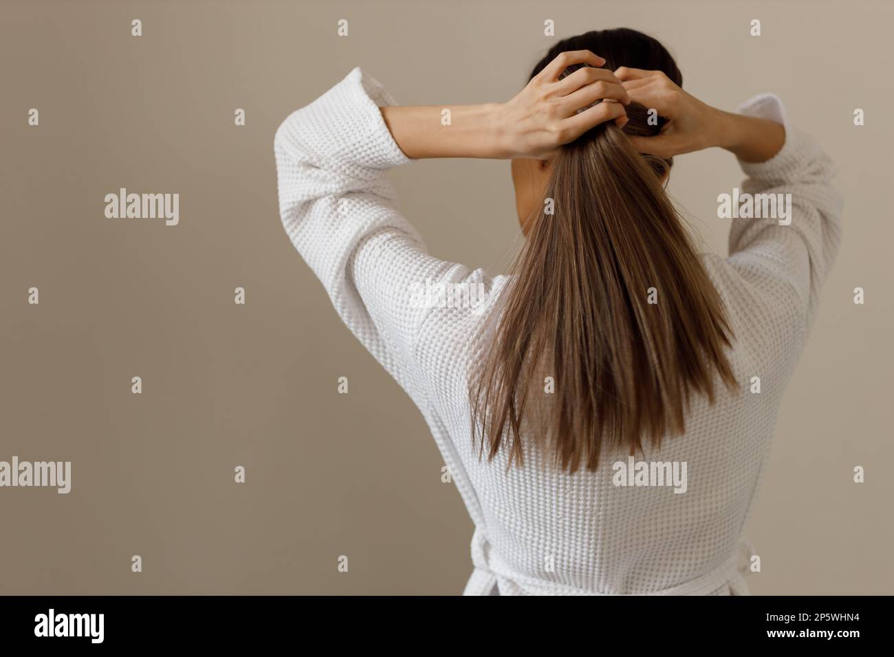 Young woman with healthy long smooth hair in white bathrobe, rear view ...