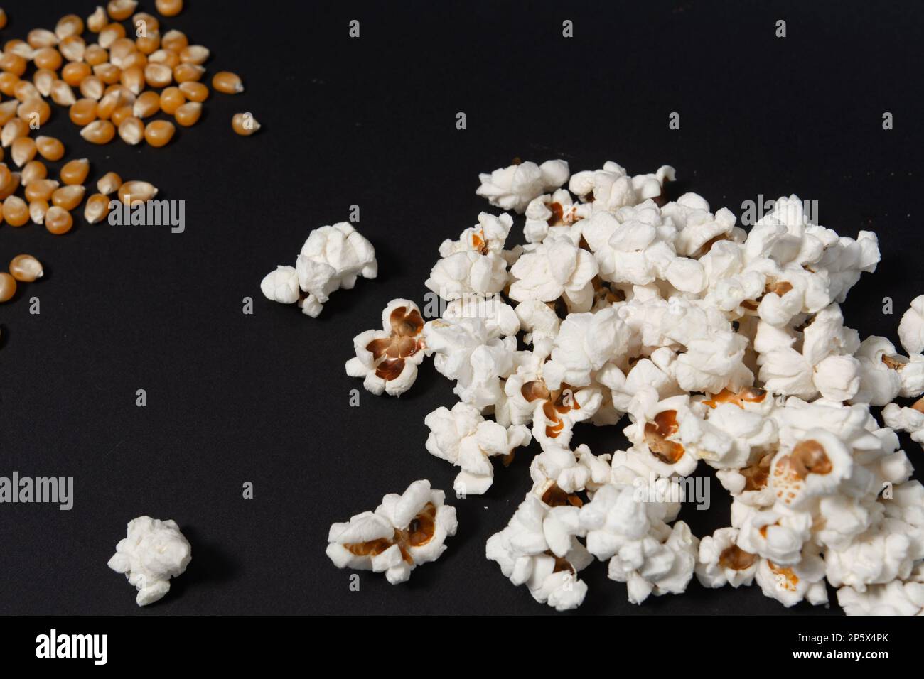 Two piles of popcorn, one pile of ready-made popcorn, another with corn ...