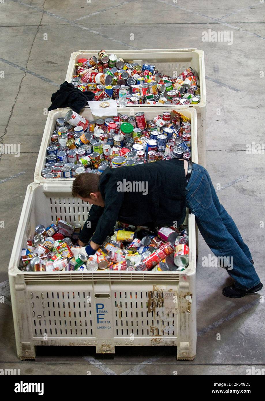 Ty Woolworth, of Irvine, sorts through a bin of cans as he volunteers ...