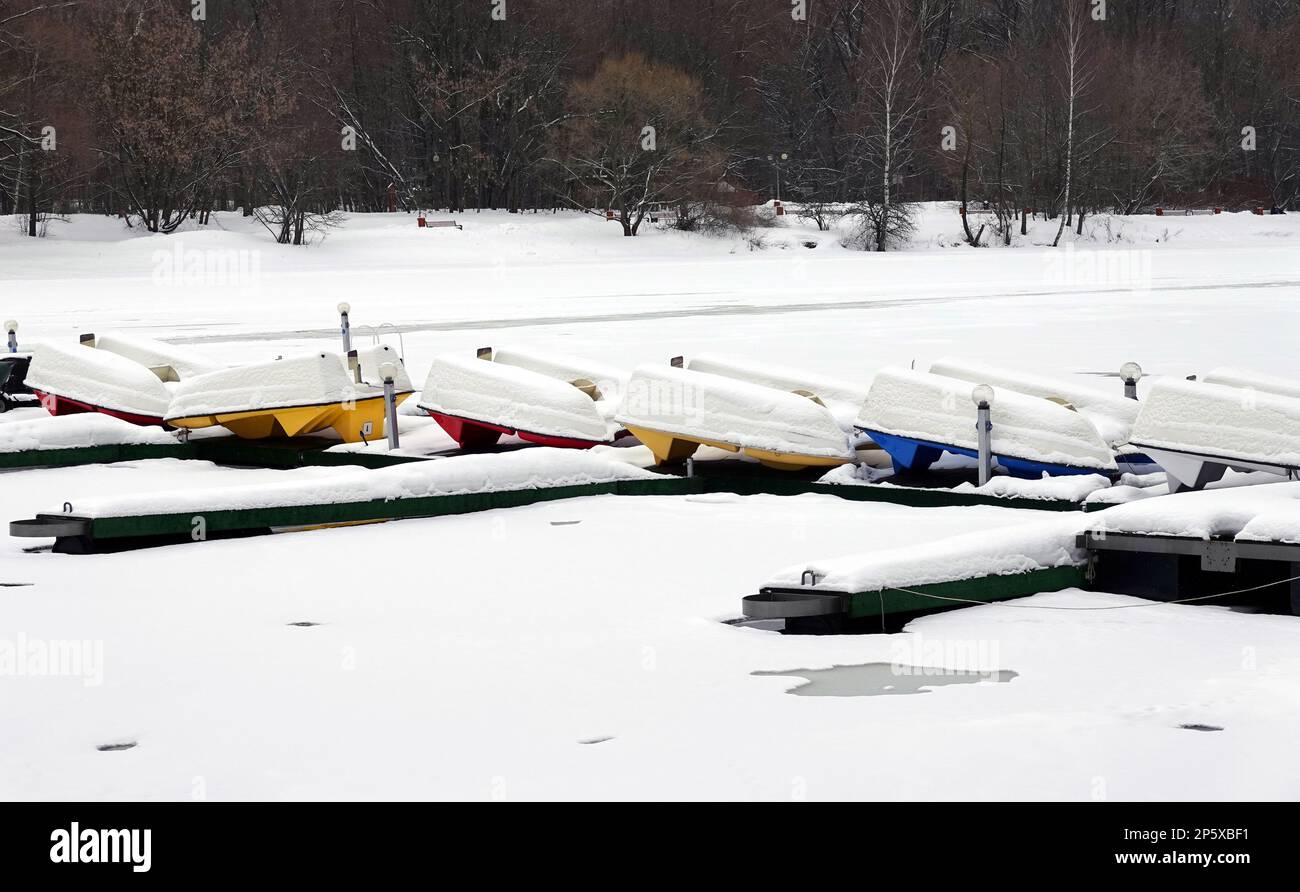 WInter landscape with many overturned boats in the snow on a dock on a ...