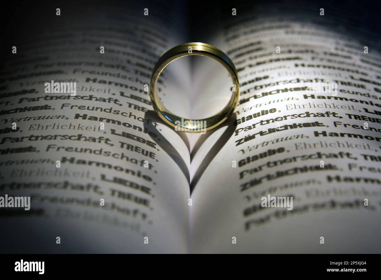 golden ring in an open book shadowing a heart Stock Photo - Alamy