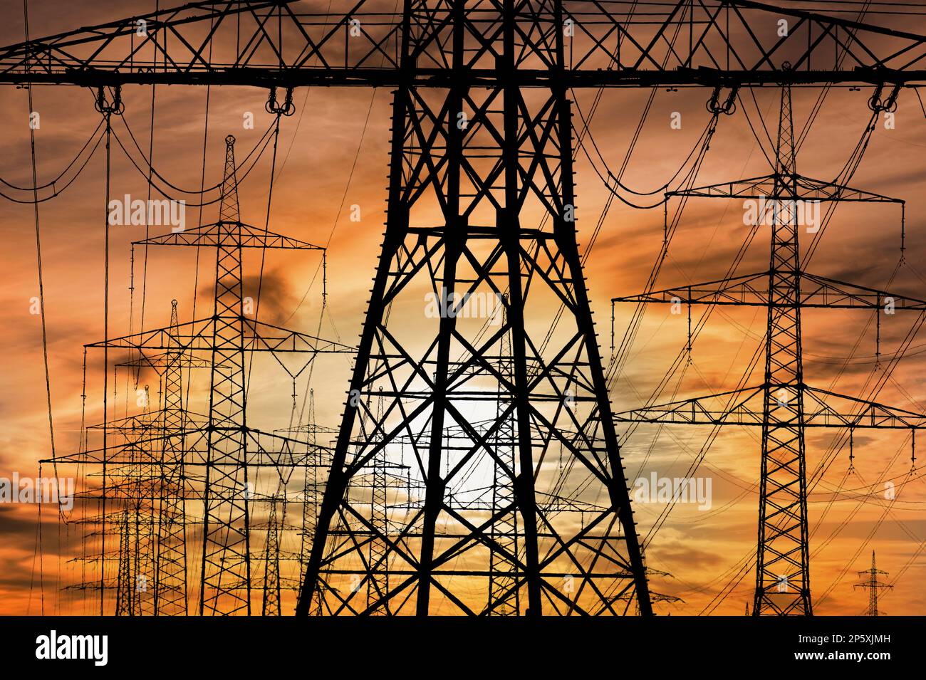 high voltage pylons for electricity and power against sky with dramatic ...