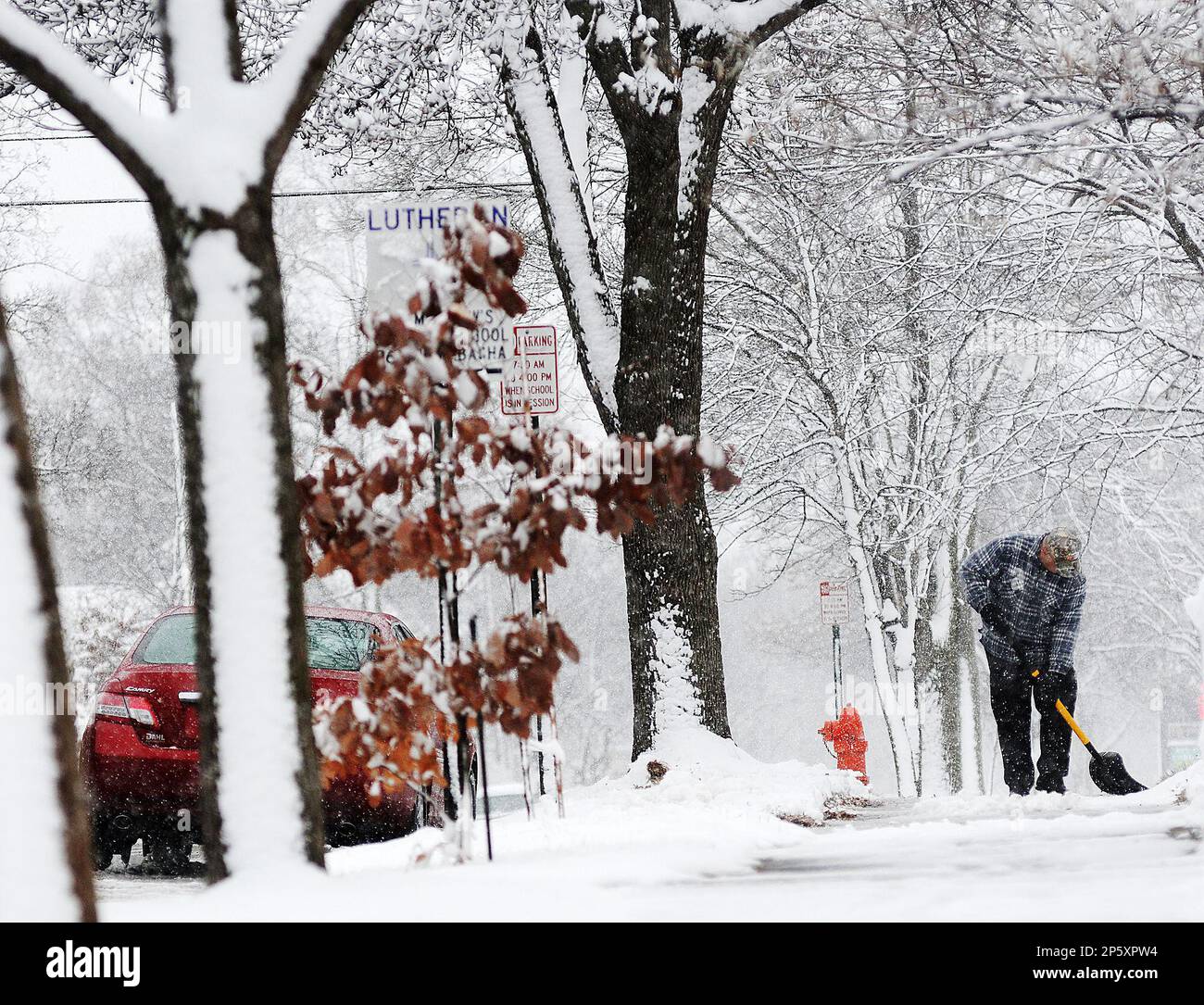 Jean Bohlinger shovels snow from the sidewalk in front of his daughter ...
