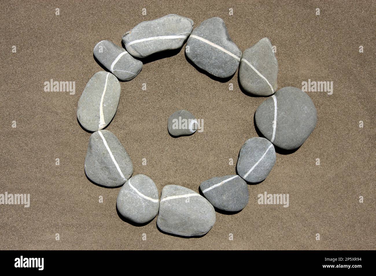 stone circle on sand made of stones with white stripe, little pebble in ...