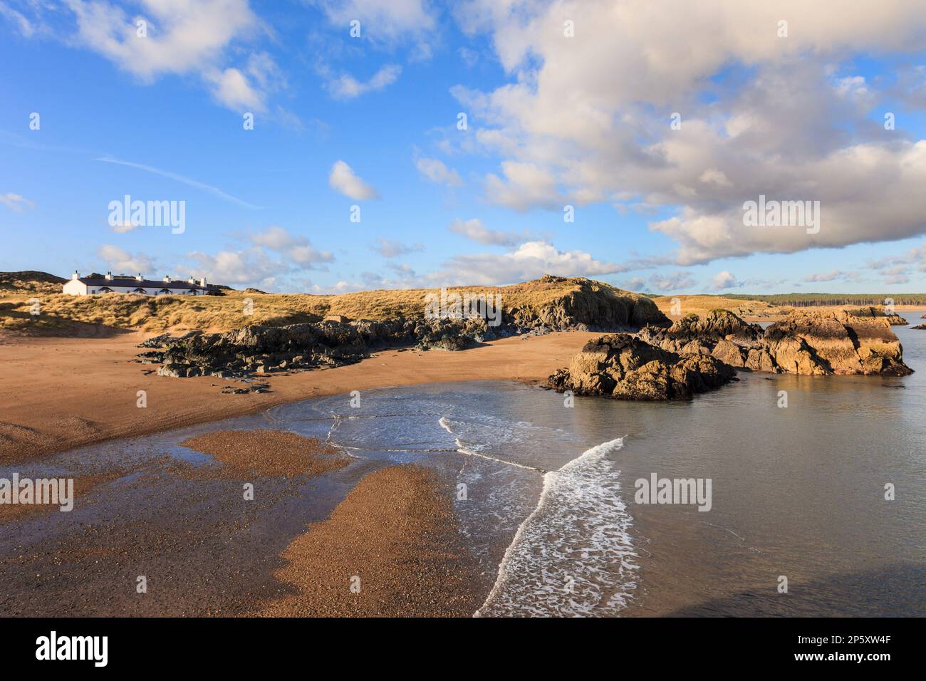 View across small sandy beach to old Pilot's cottages on Llanddwyn ...