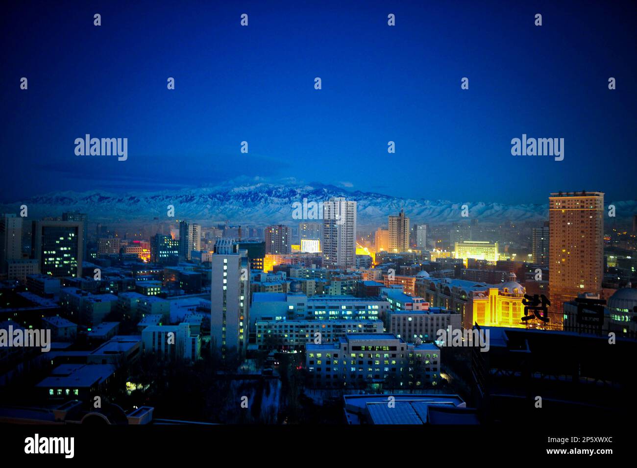 A night view of the Urumqi city and Tianshan Mountain after a snow ...