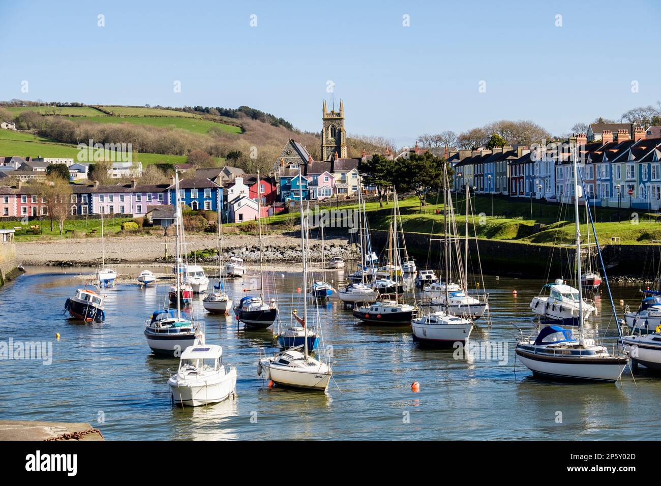 View along Afon Aeron River estuary to church with boats moored in ...