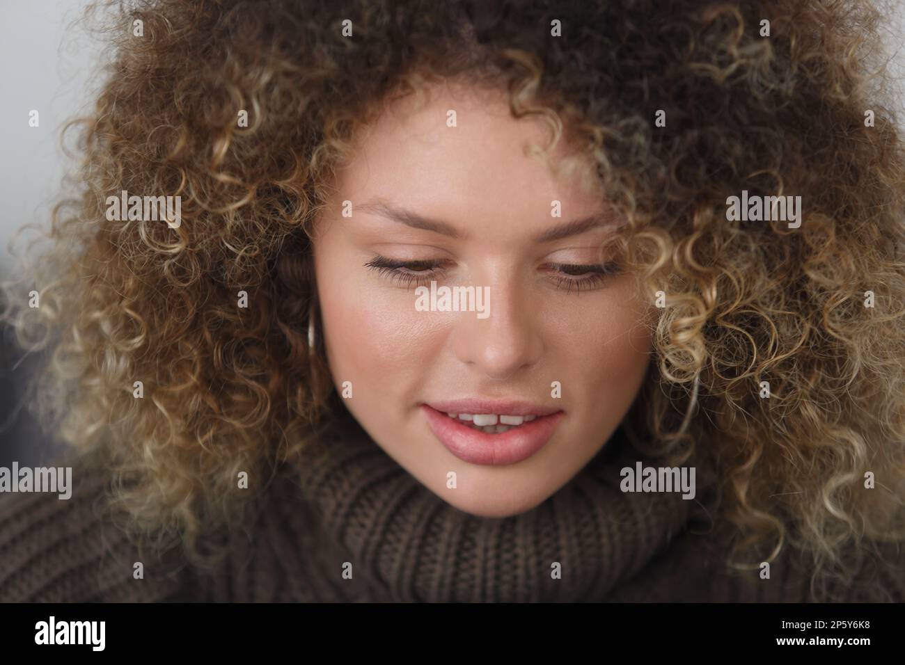 Portrait of beautiful white woman with curly hair working on a computer ...