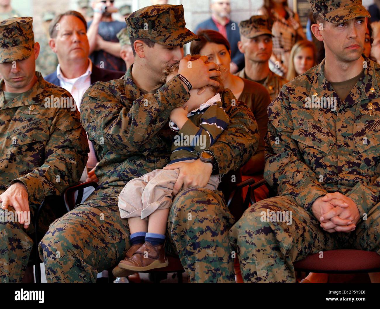 U.S. Navy Petty Officer 2nd Class Patrick Quill, center, kisses his 2 ...