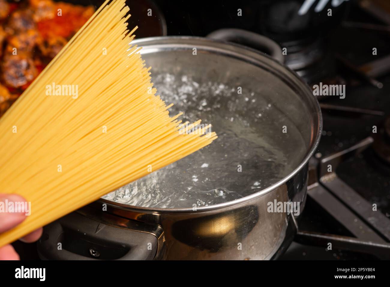 Dip spaghetti into boiling water in a saucepan. Pasta cooking Stock ...