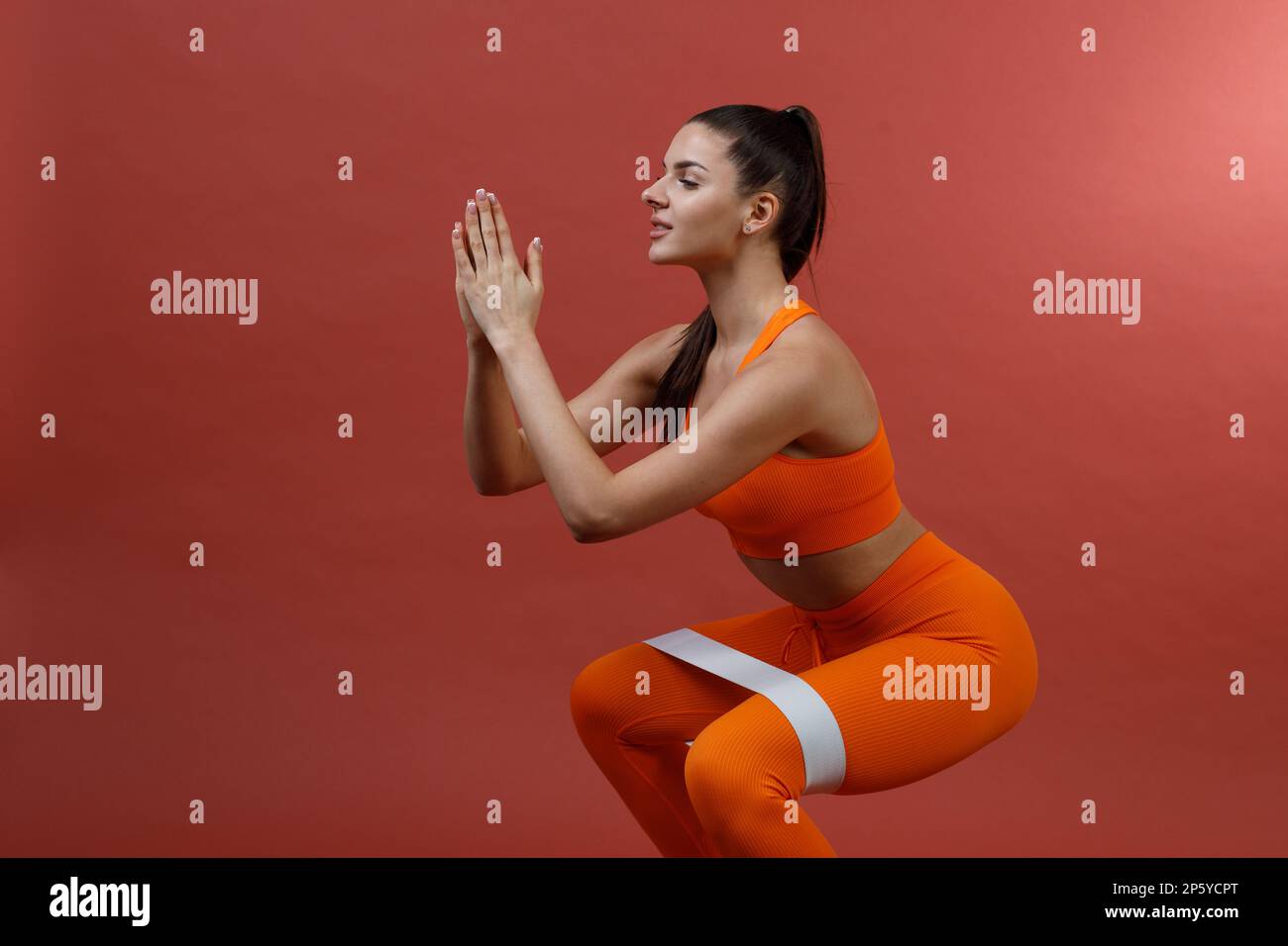 Young smiling woman doing sit ups with expander for legs and hands in ...