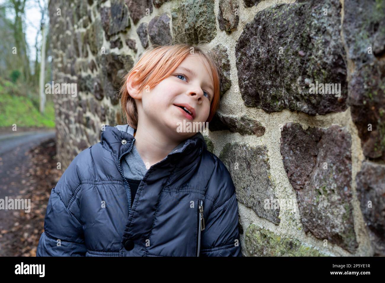 Smiling contented boy near the stone wall. A boy of nine and ten years ...
