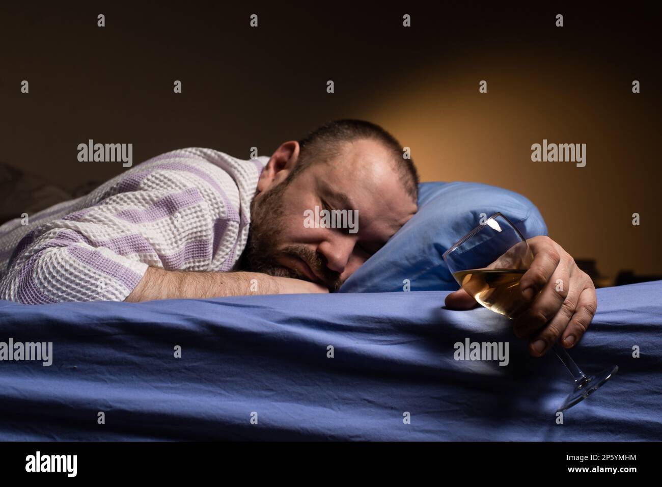 A man alone with a glass of wine in bed. Alcoholism, loneliness. Drink ...