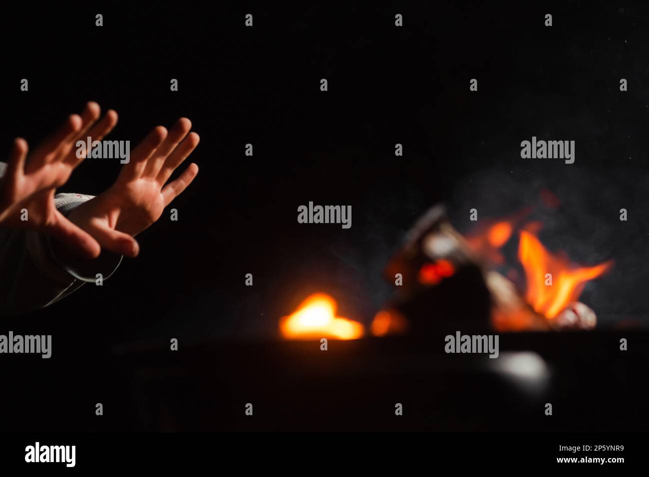 The child's hands warm themselves near the fire of the barrel in the ...