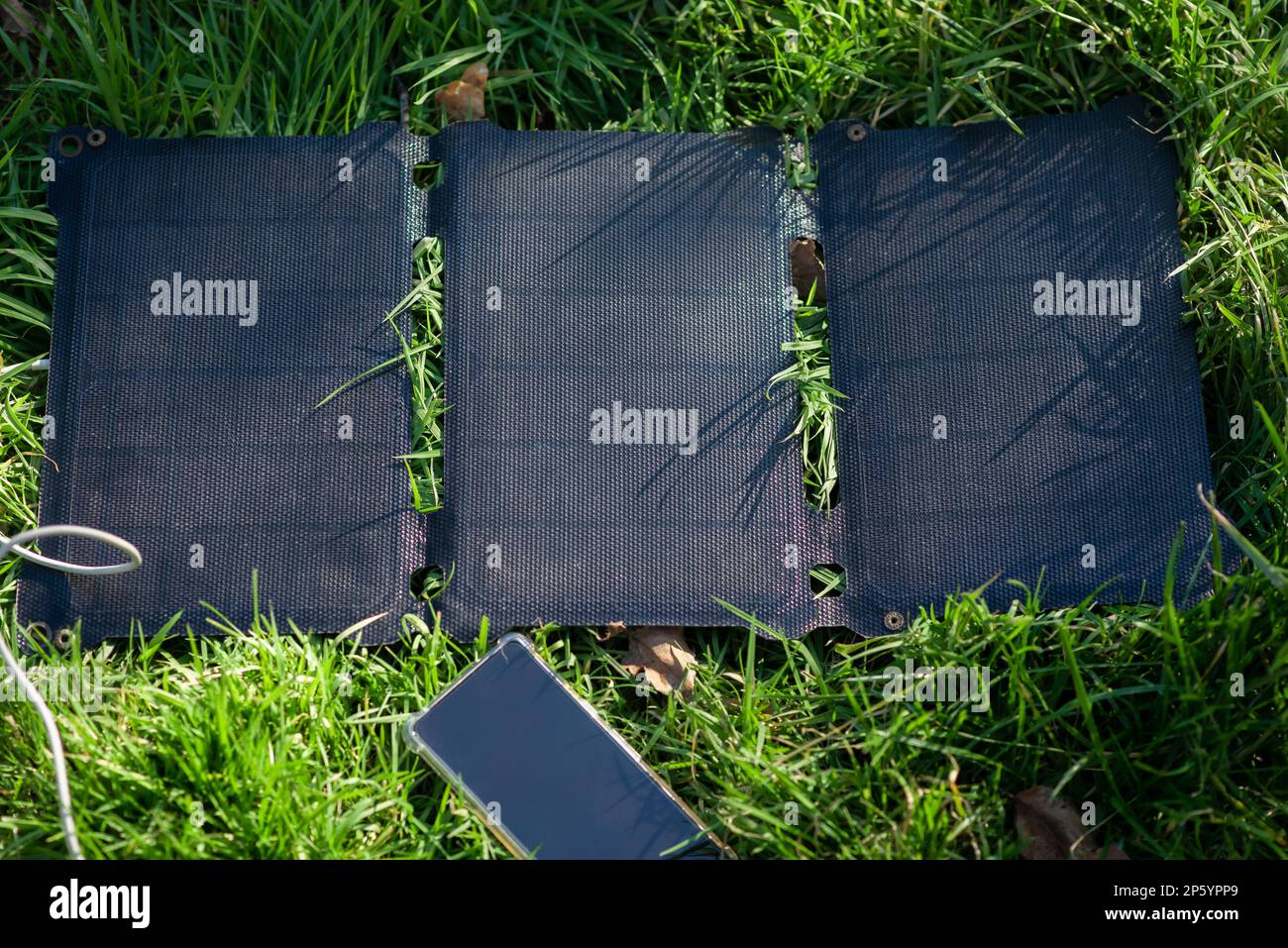 Portable solar battery and mobile phone on green grass. Charging ...