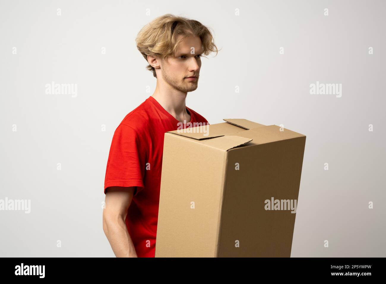 Delivery man holding a cardboard boxes and smiling while standing ...