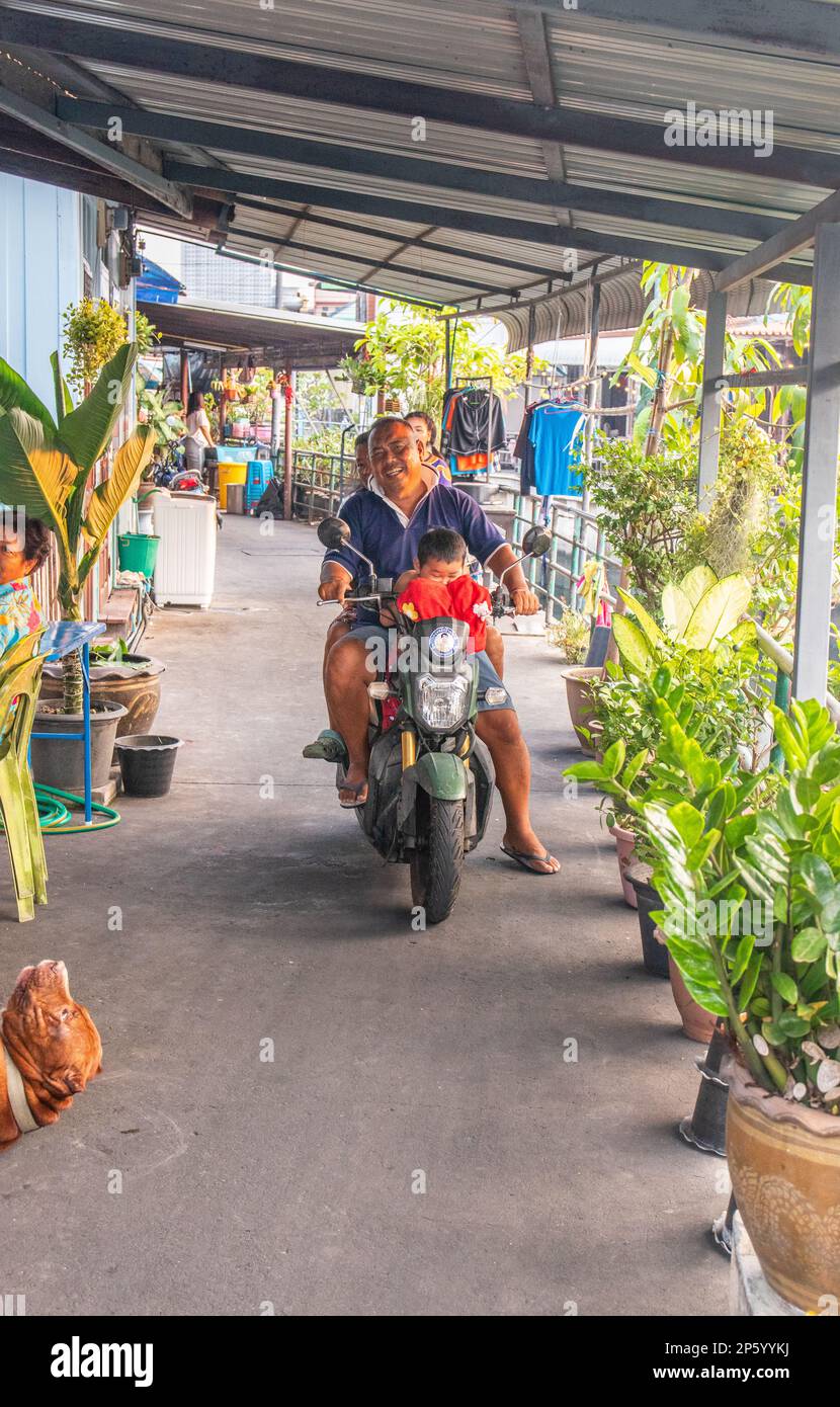 Several Thai people with a dog and a motorbike on a narrow path in a ...