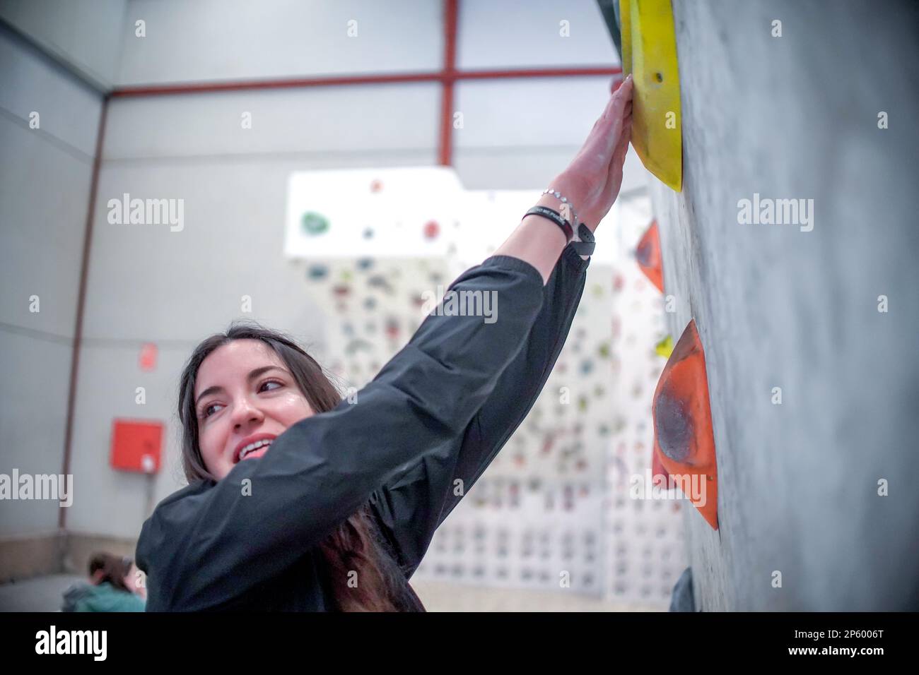 Woman climbing indoor safely in climbing wall. Bouldering sportswomen ...