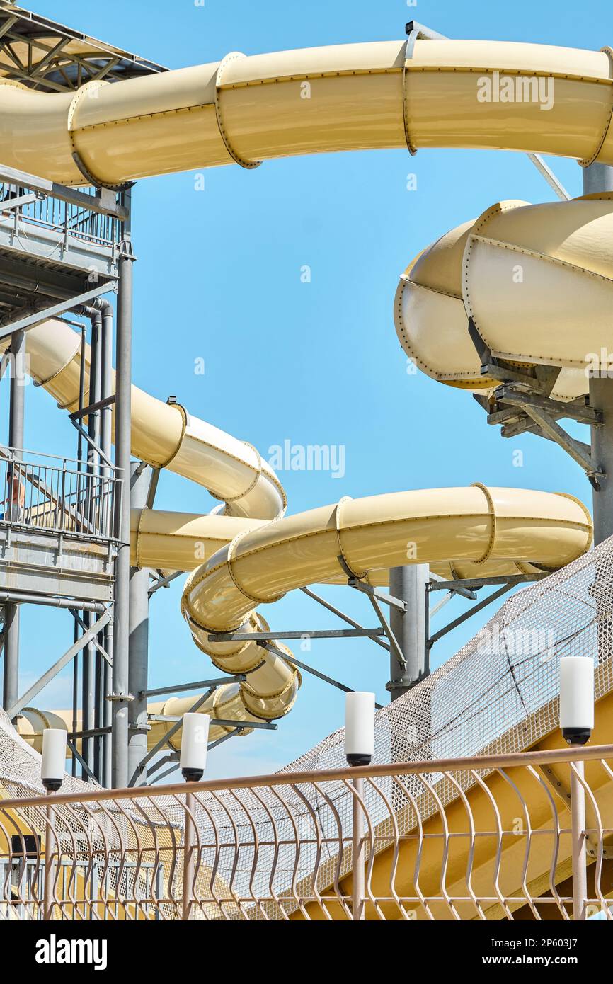 Water park slide pipes and railing with lamps against clear blue sky ...
