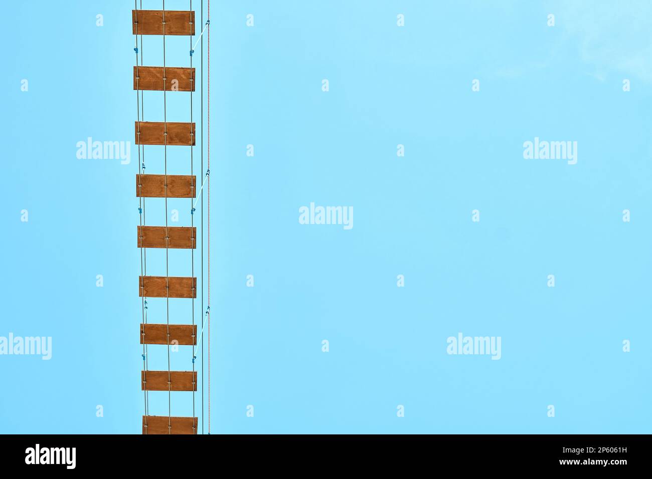 Long rope bridge with wooden planks against clear blue sky. Fun ...