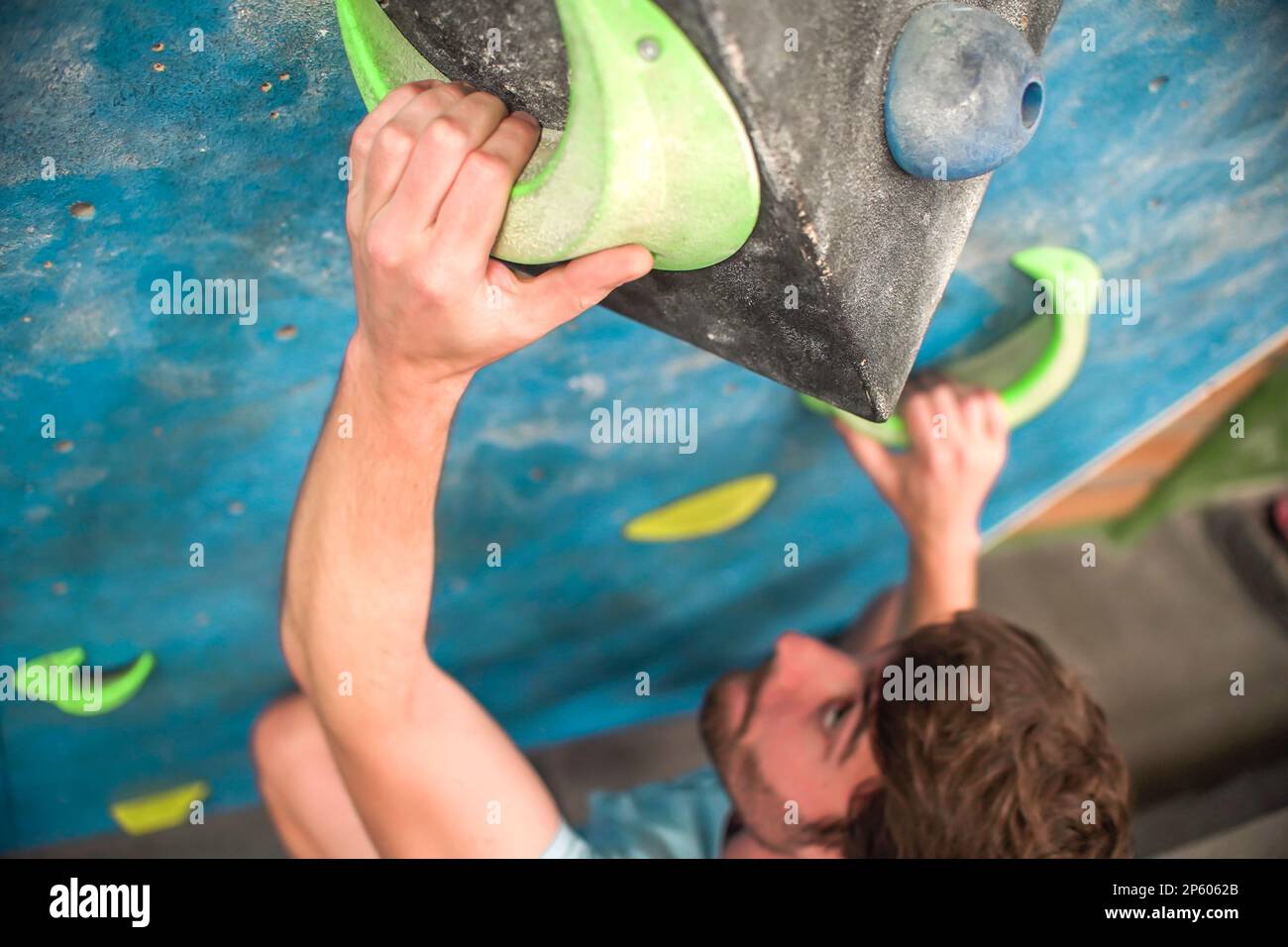 Sportsman climbing indoor safely in climbing wall. Bouldering man ...