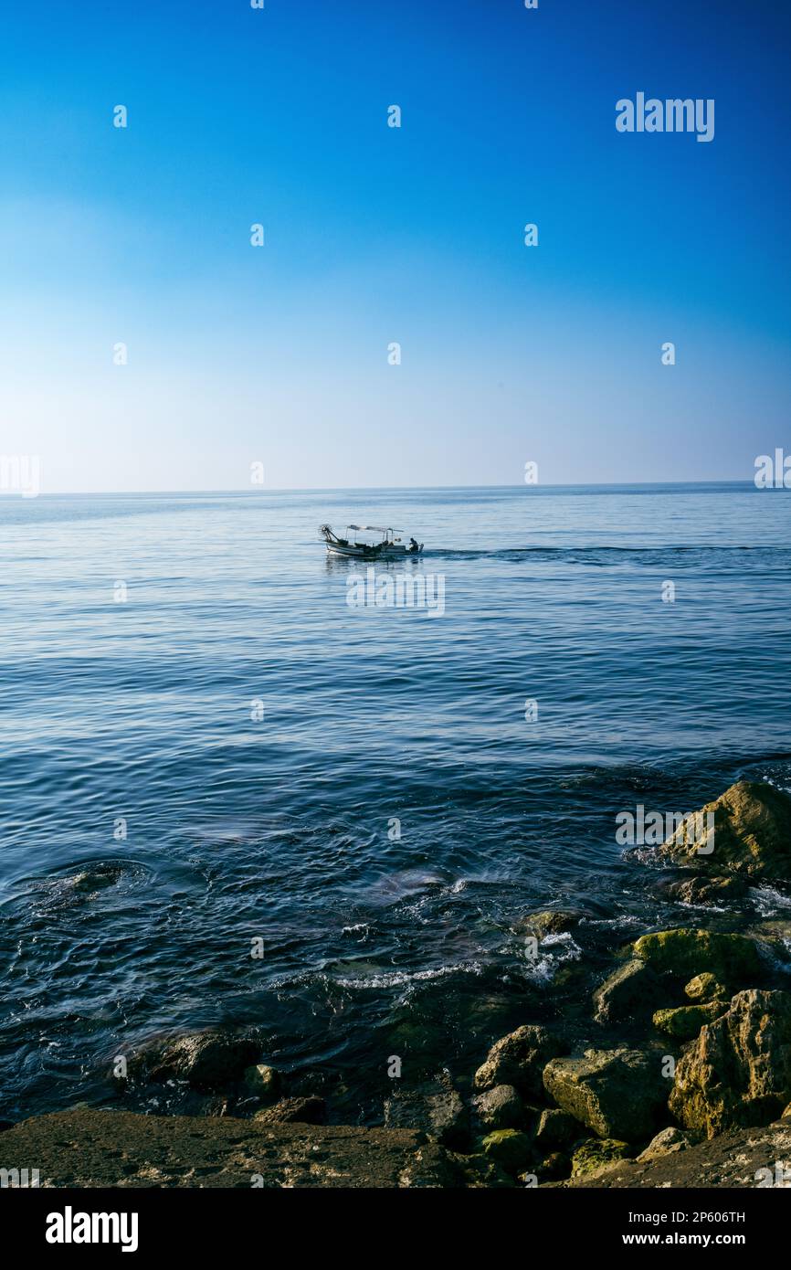 Boating scene with a boat near a beach shoreline in a vertical format ...