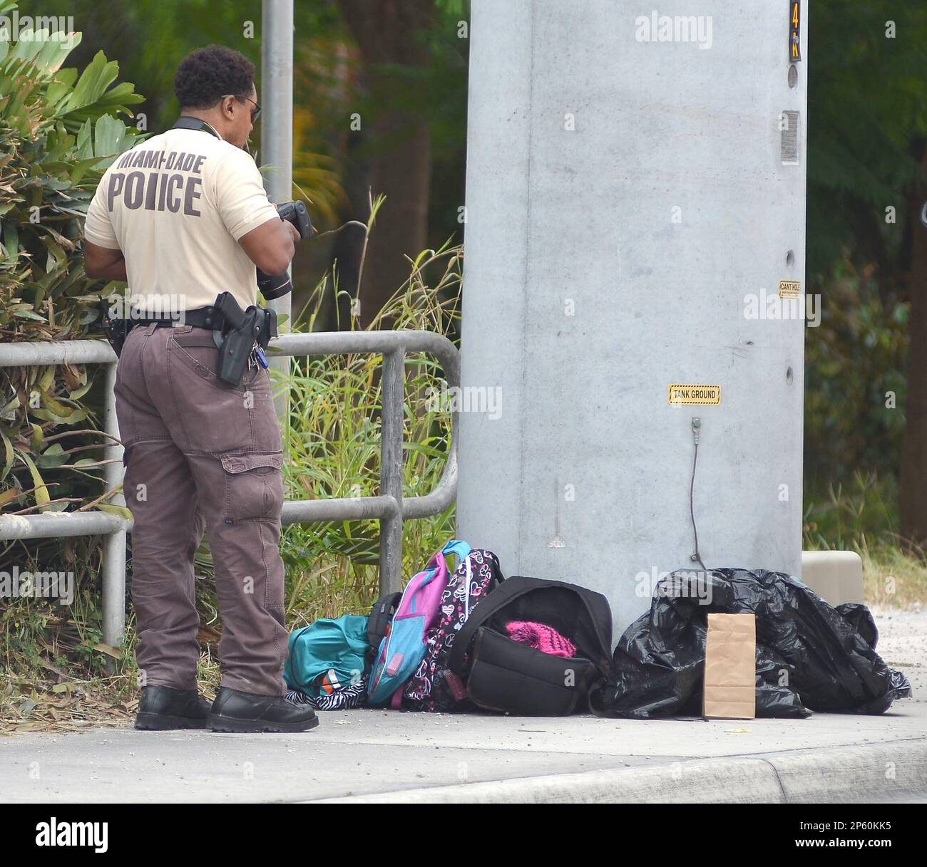 A police investigator photographs school backpacks taken off a school ...