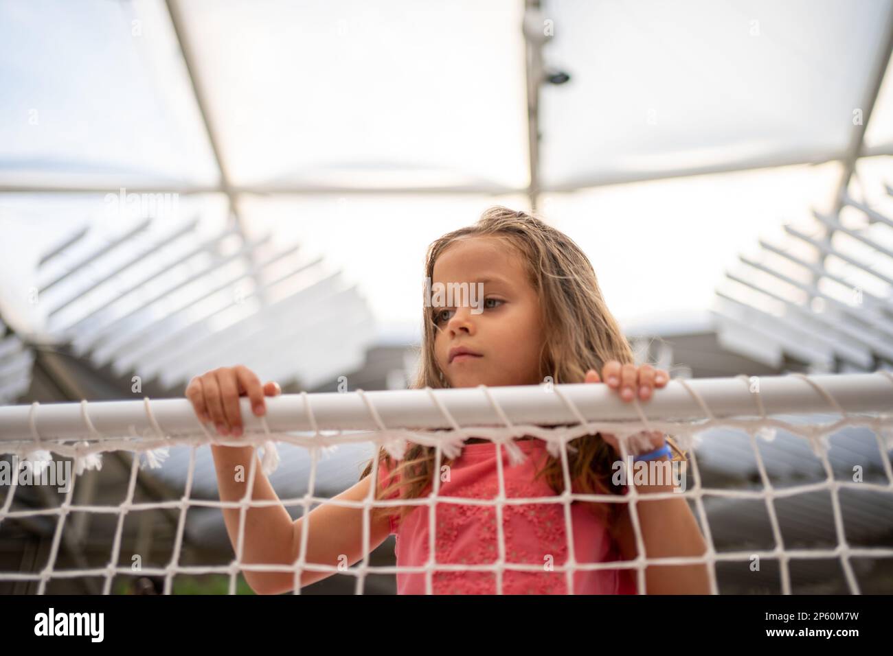 Little girl lean on net looking away with sad face emotion. Lost ...