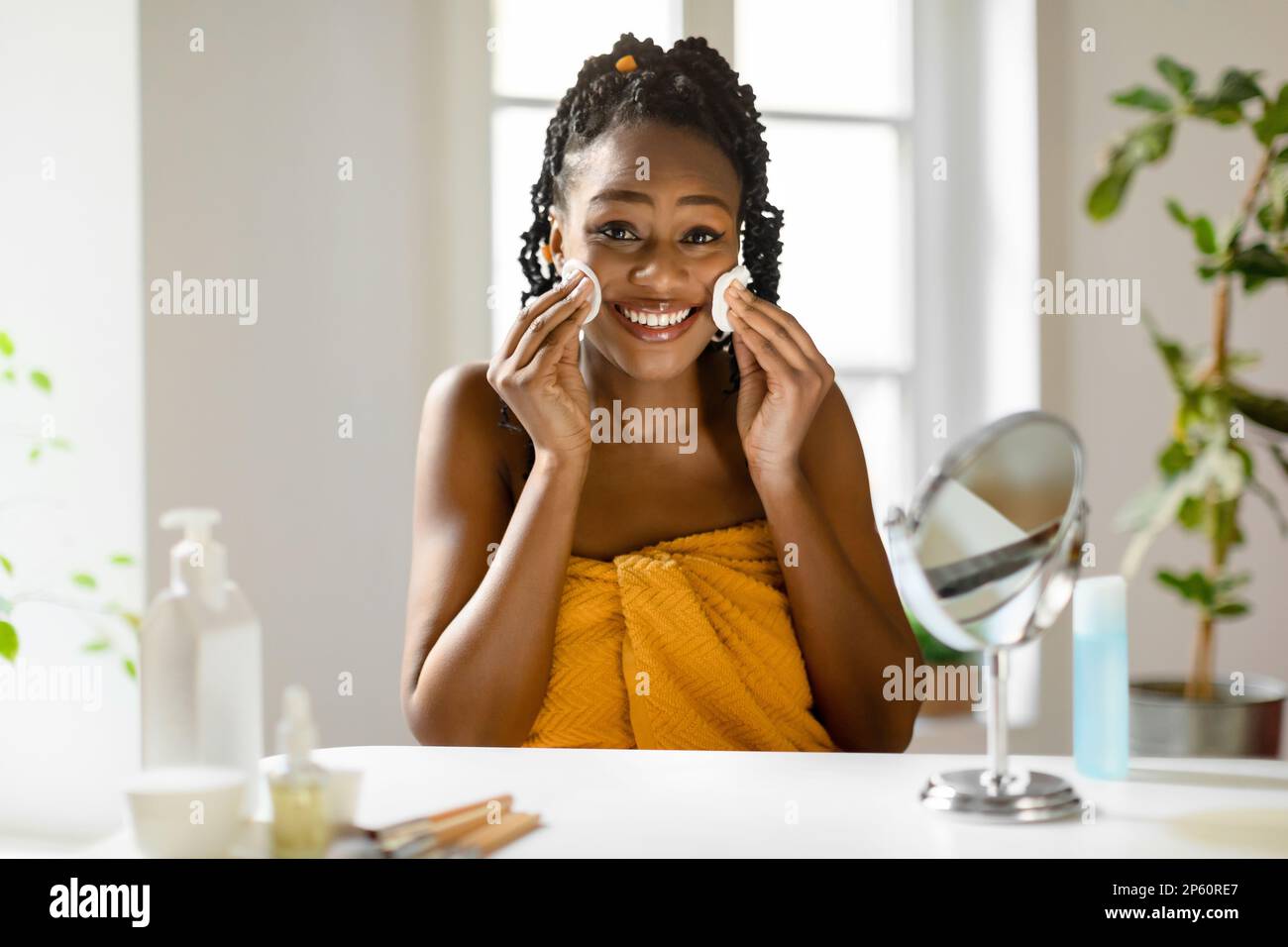Happy beautiful black lady sitting in front of mirror in bedroom ...