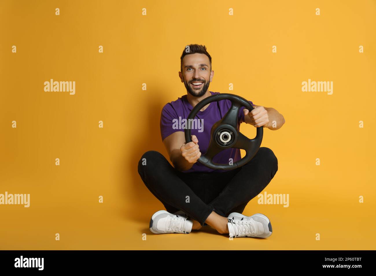 Happy man with steering wheel on yellow background Stock Photo - Alamy
