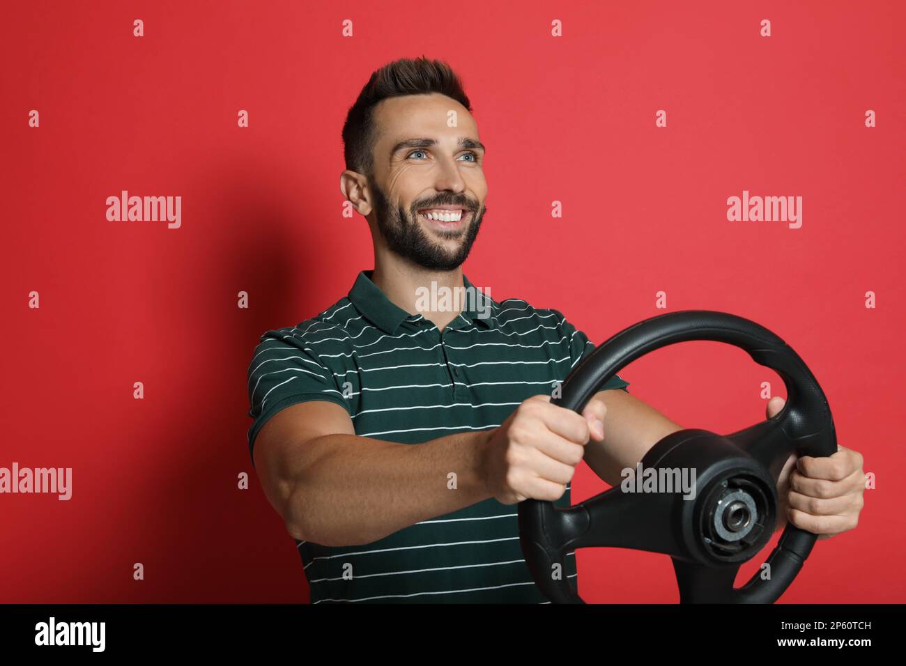 Happy man with steering wheel on red background Stock Photo - Alamy