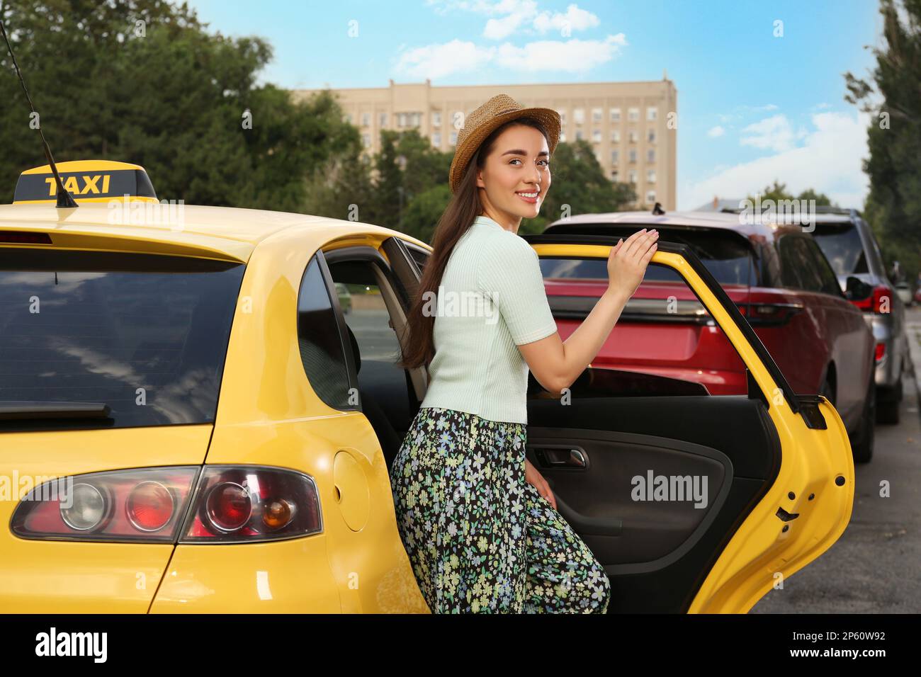 Beautiful young woman getting out of taxi on city street Stock Photo ...
