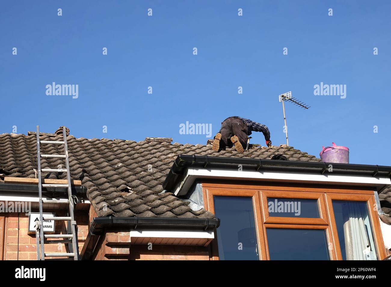 A roofer repairing ridge tiles on the roof of a domestic house Stock ...