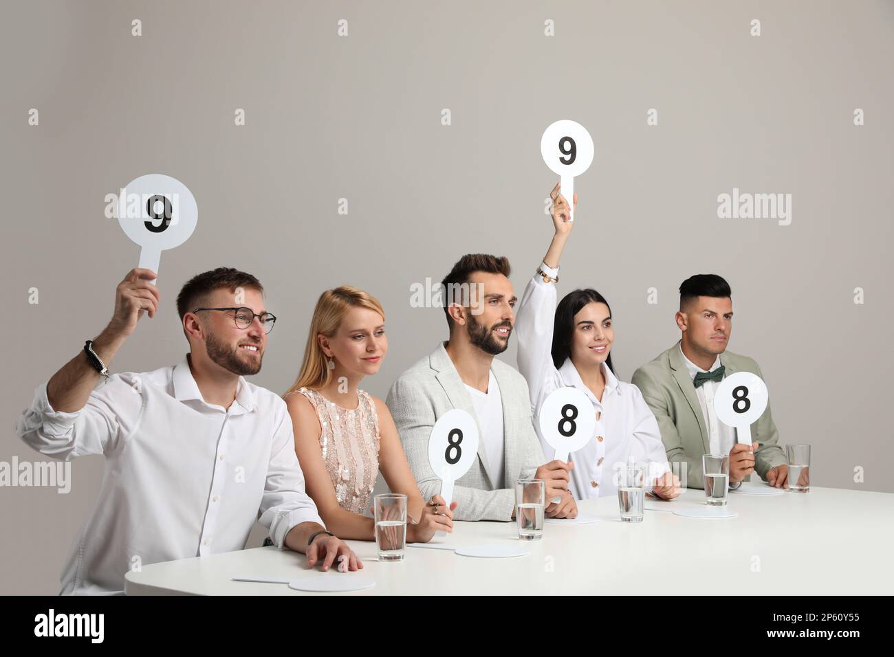 Panel of judges holding different score signs at table on beige ...