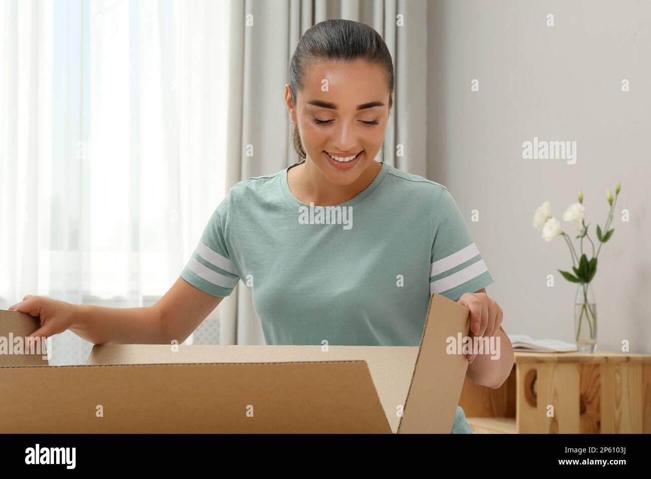 Happy young woman opening parcel at home. Internet shopping Stock Photo ...