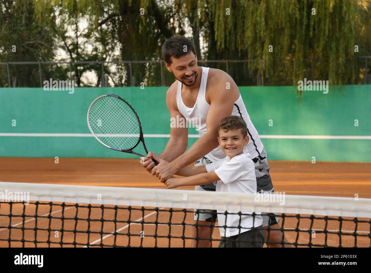 Father teaching son to play tennis on court Stock Photo - Alamy
