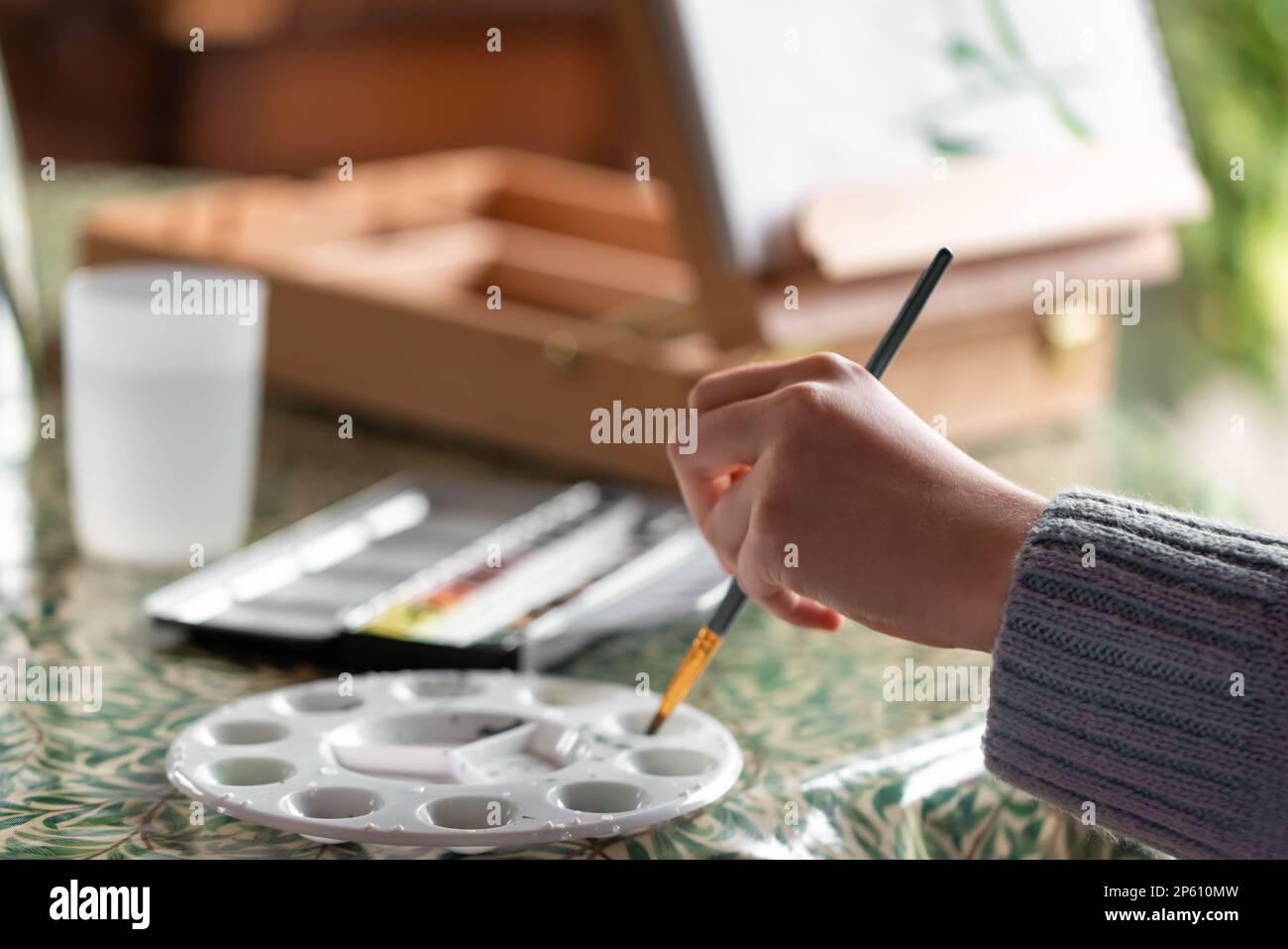 Young left-handed girl painting still life with flowers mixing ...