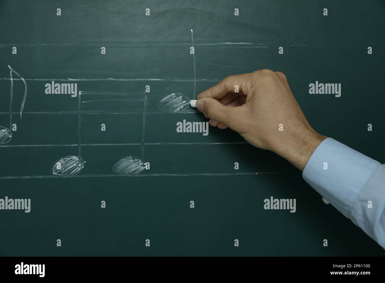 Teacher writing music notes with chalk on greenboard, closeup Stock ...
