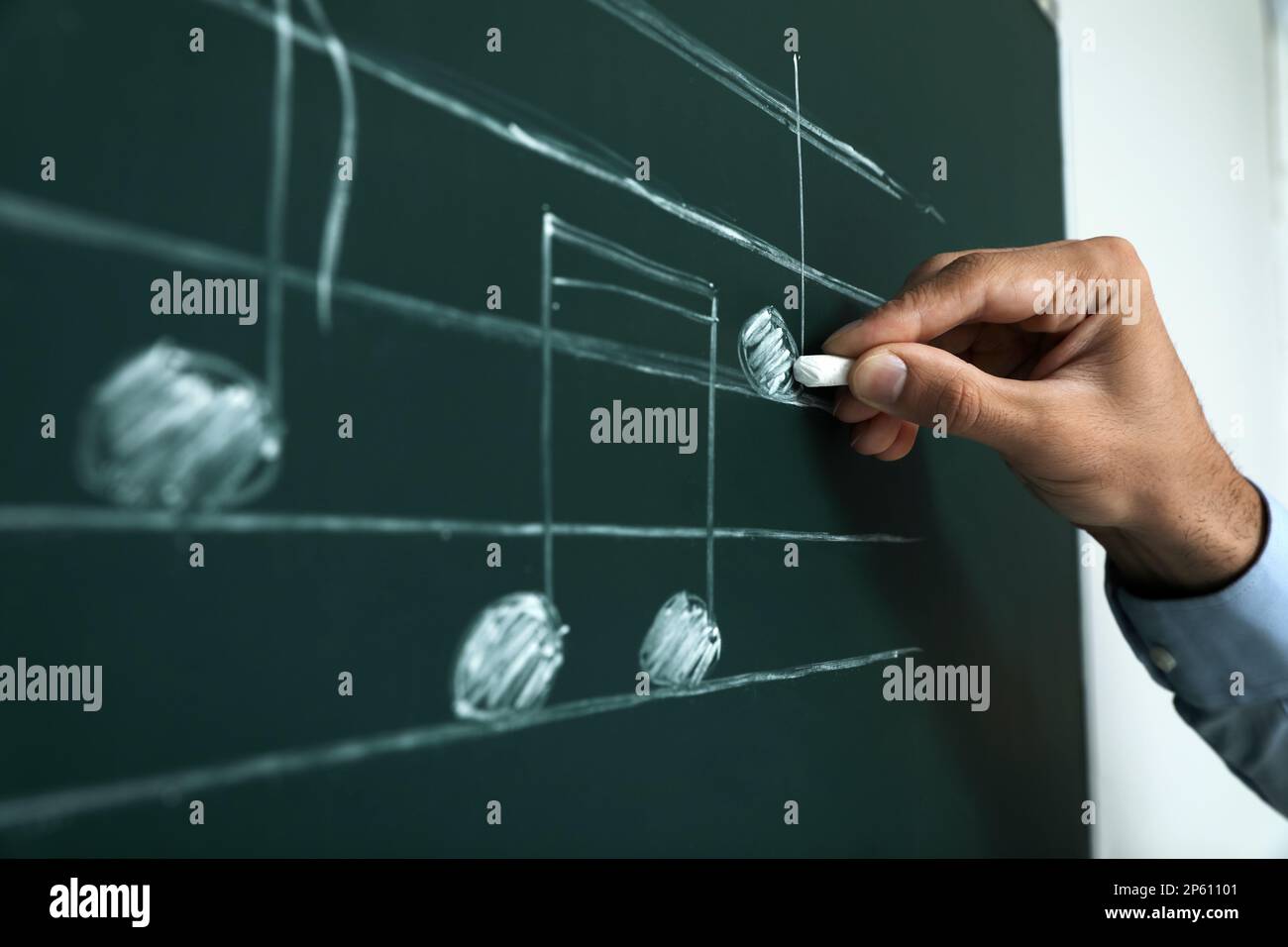 Teacher writing music notes with chalk on greenboard, closeup Stock ...